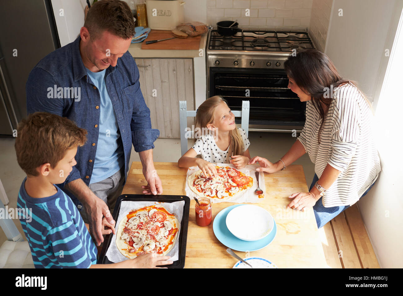 Family At Home In Kitchen Making Pizzas Together Stock Photo - Alamy