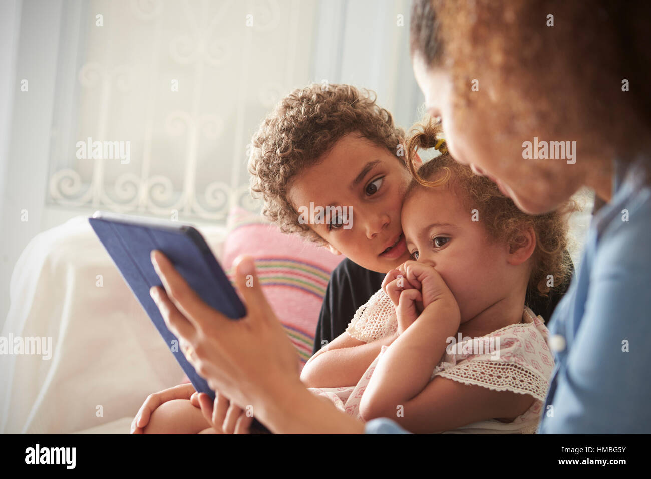 Mother And Children Sitting On Sofa Using Digital Tablet Stock Photo ...