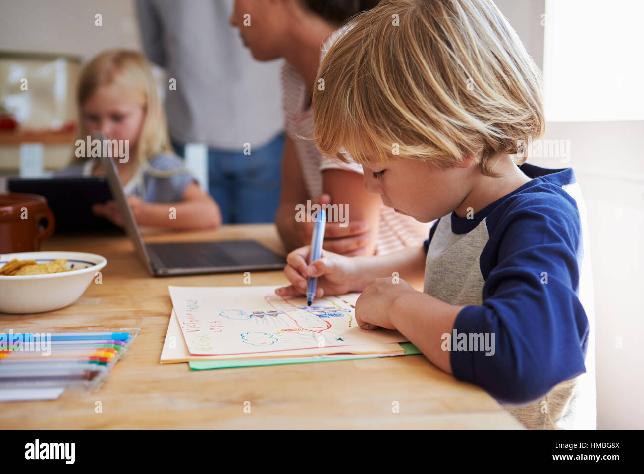 Kids working at kitchen table with their mother, close up Stock Photo ...