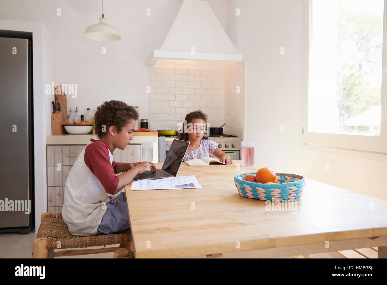 Brother and sister doing homework at kitchen table Stock Photo - Alamy