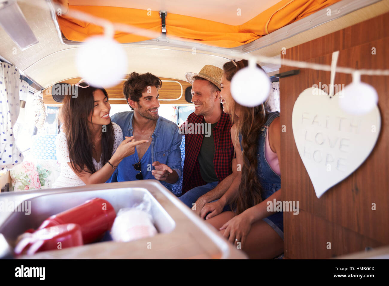 Four friends on a road trip talk in the back of a camper van Stock ...
