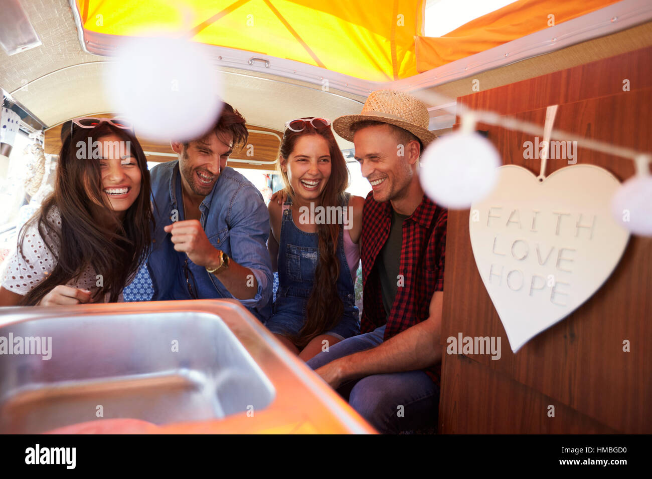 Four friends laughing in the back of a camper van Stock Photo - Alamy