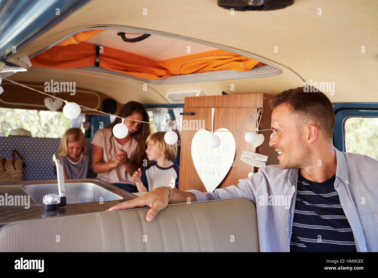Dad in driving seat of camper van looks back at his family Stock Photo ...