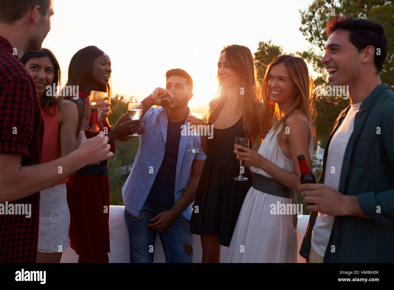 Adult friends socialising at a party on a rooftop at sunset Stock Photo ...