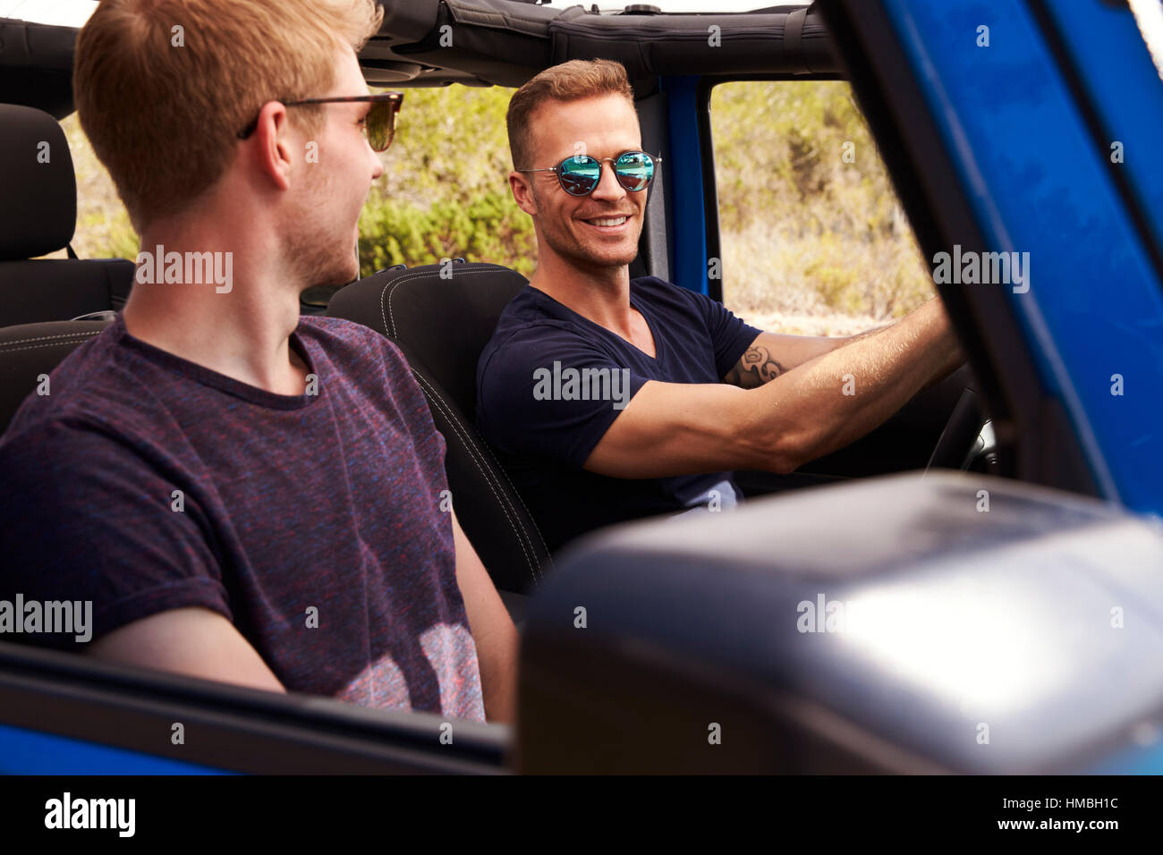 Two Male Friends Driving Open Top Car On Country Road Stock Photo - Alamy