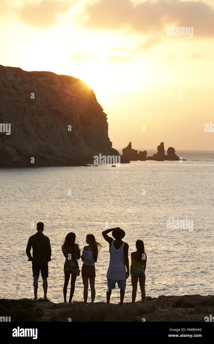 Rear View Of Friends Standing On Cliff Watching Sunset Stock Photo - Alamy