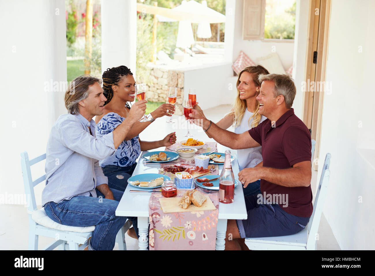 Two couples at a dinner table on a patio raise their glasses Stock ...