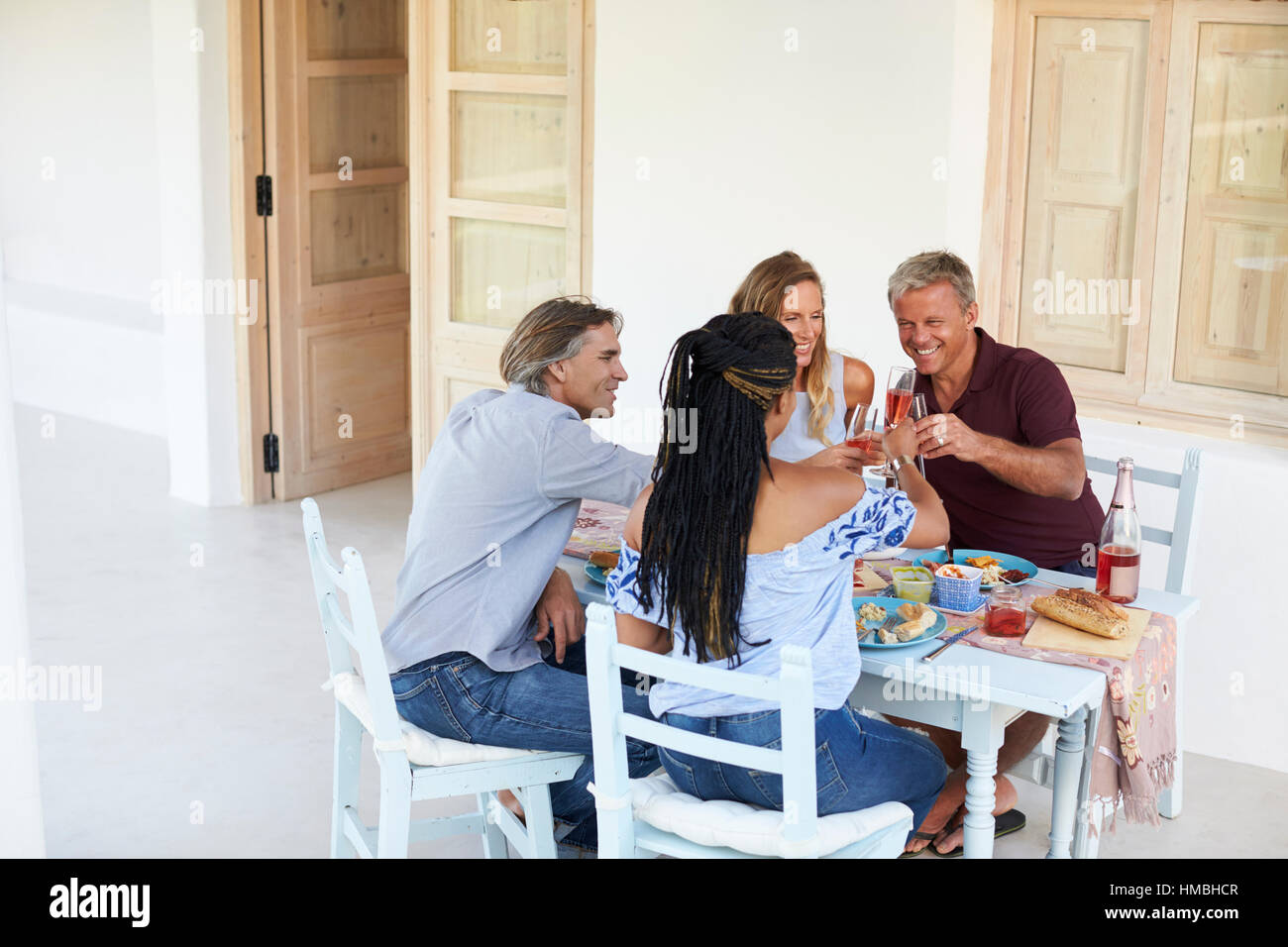 Two couples at dinner on a patio make a toast, back view Stock Photo ...
