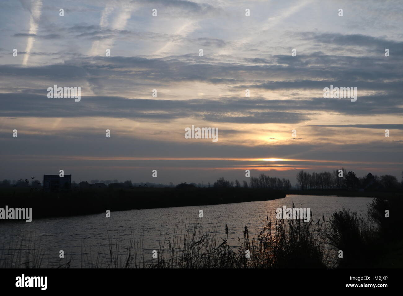 sun behind clouds reflecting on water Stock Photo - Alamy