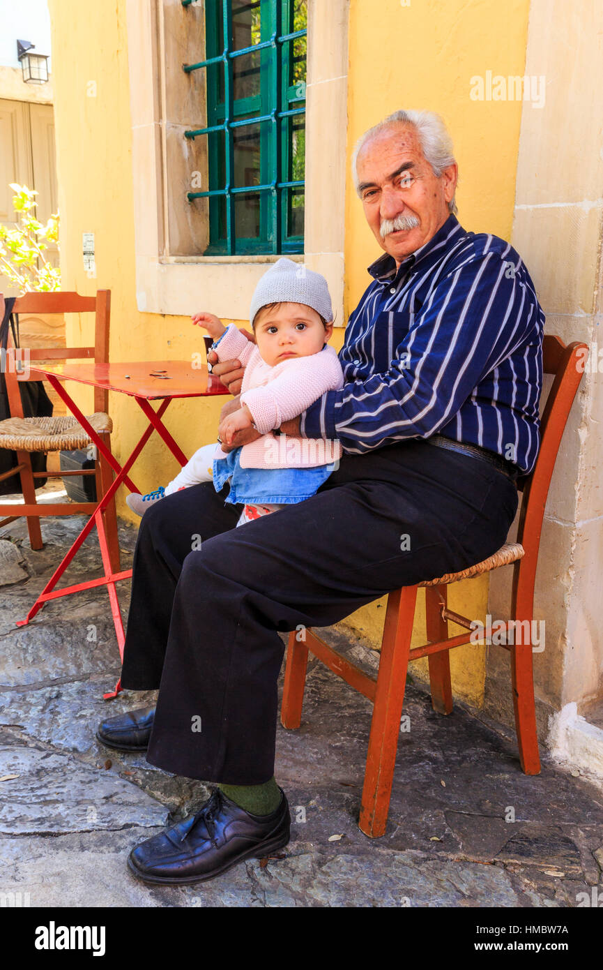 old Greek man sitting with baby grand daughter on his knee, crete ...