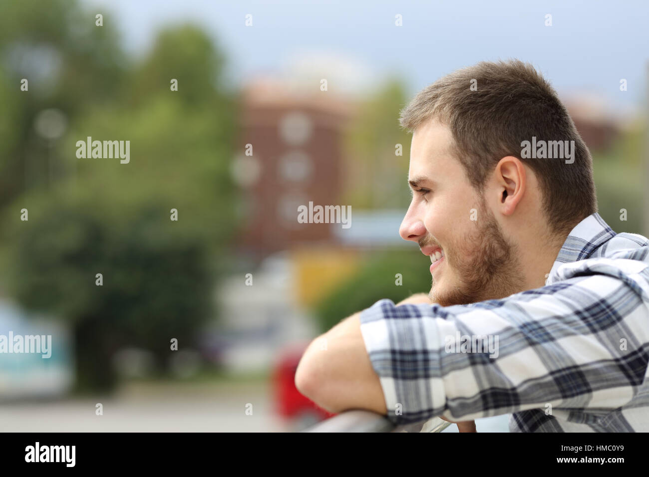 Side view of a happy man looking away and enjoying urban views from a ...
