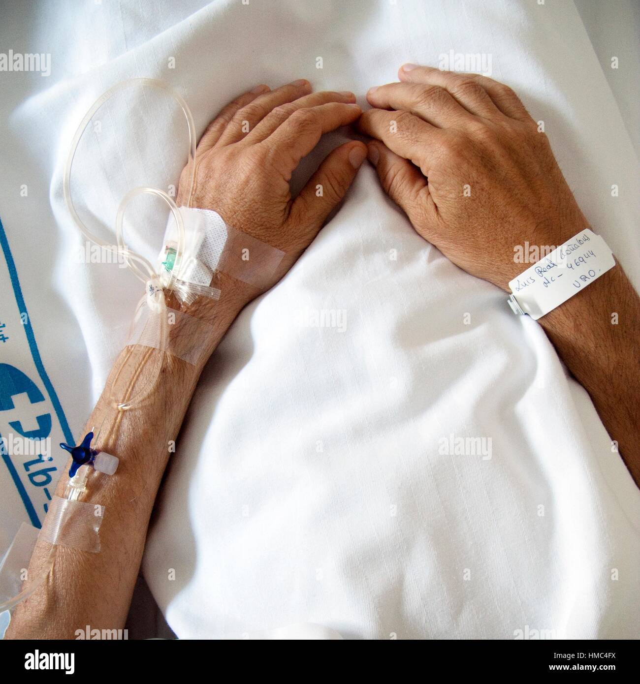 Closeup of a hand of a patient in a hospital bed with connections serum ...