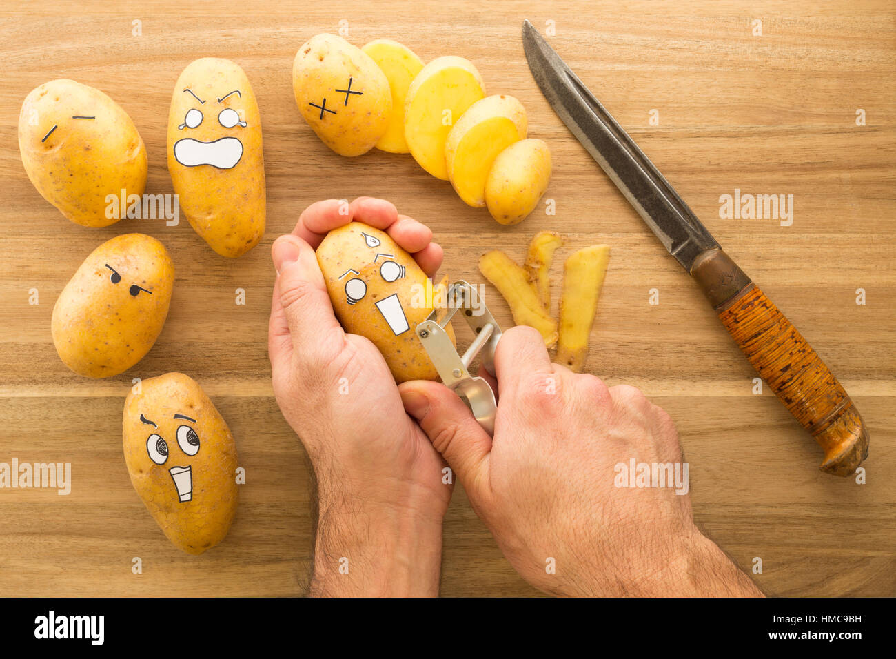 Fresh potatoes with cartoon style faces laying on a brown cutting board ...