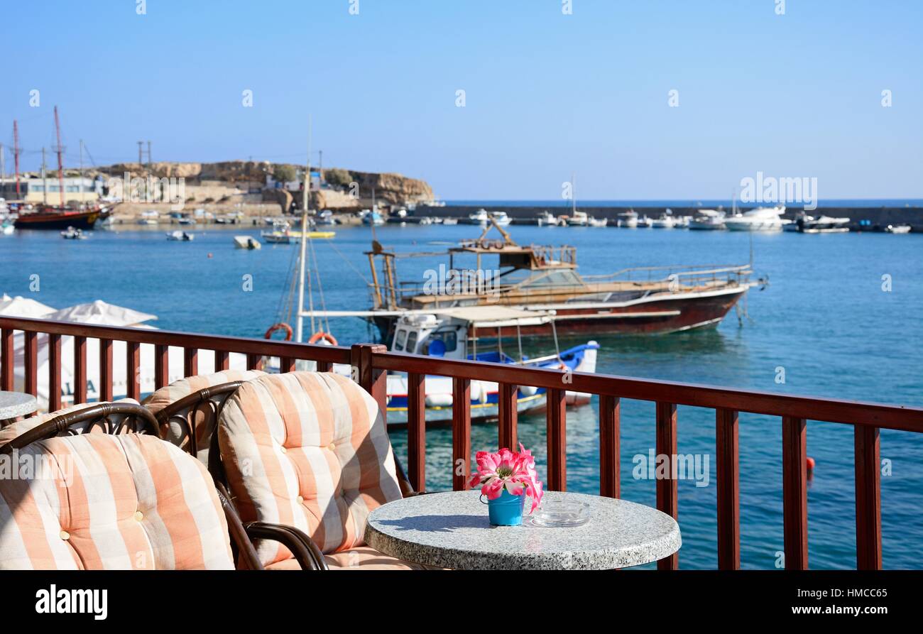Tables and chairs at a waterfront bar with views across the harbour ...