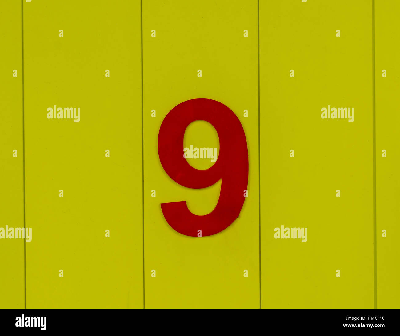 The number nine (9), in red, on a yellow surface which is made out of ...