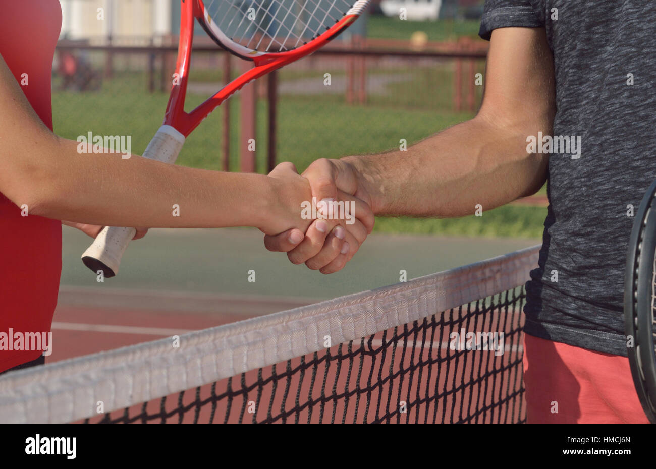 Young players shaking hands on tennis court, only hands can be seen ...