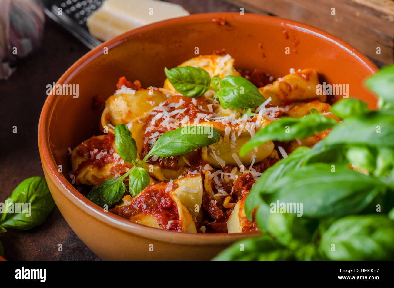 Homemade tortellini with tomato sauce, herbs and garlic in, topped with parmesan cheese Stock ...