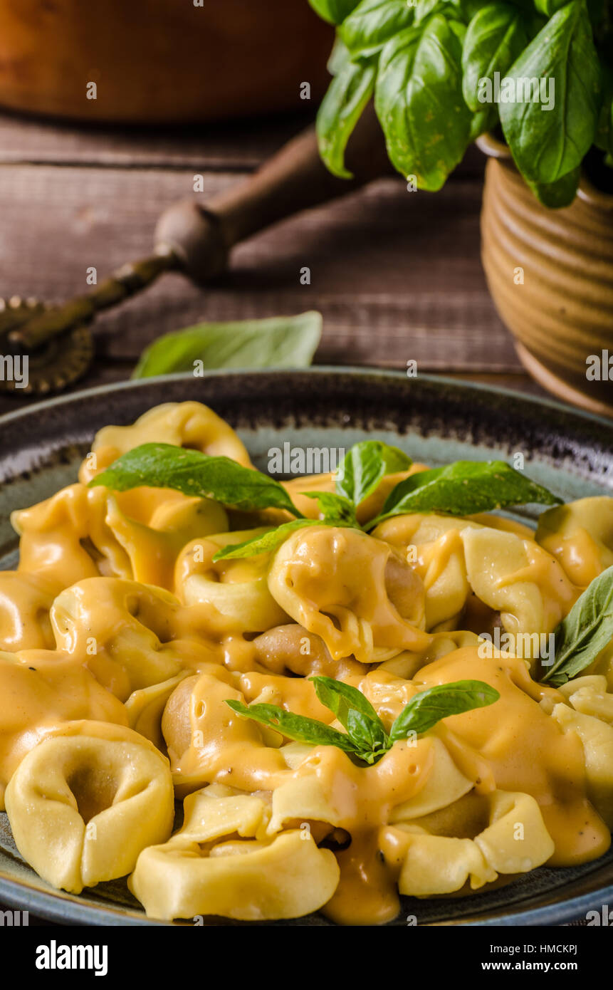 Tortellini with cheese sauce, basil and herbs Stock Photo - Alamy
