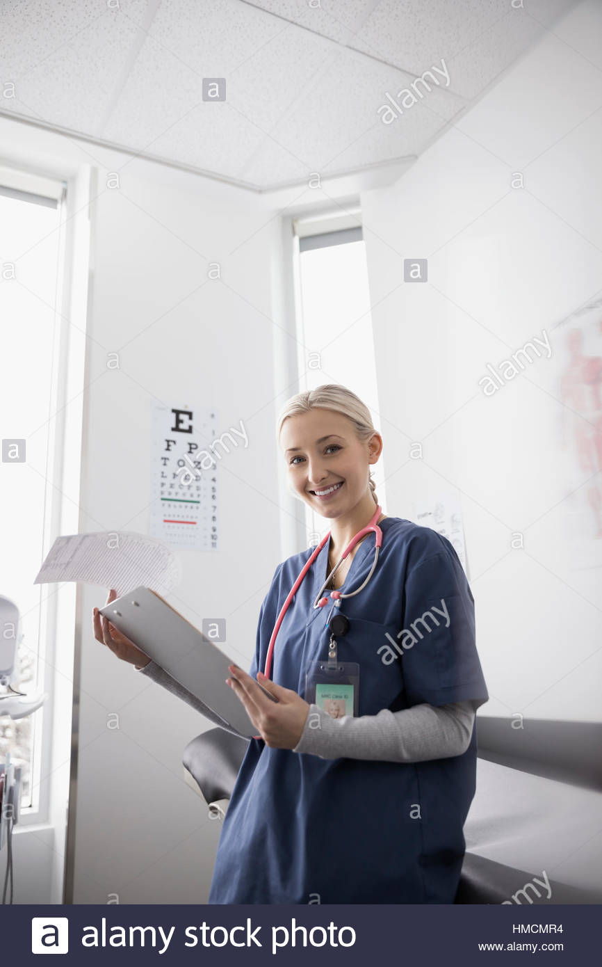 Portrait smiling, confident female nurse with clipboard reviewing ...