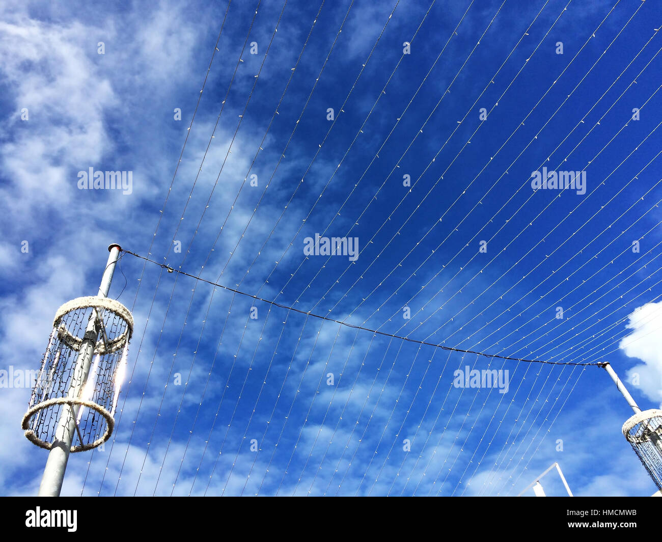 Strings of Christmas lights in the daytime against a blue sky with ...
