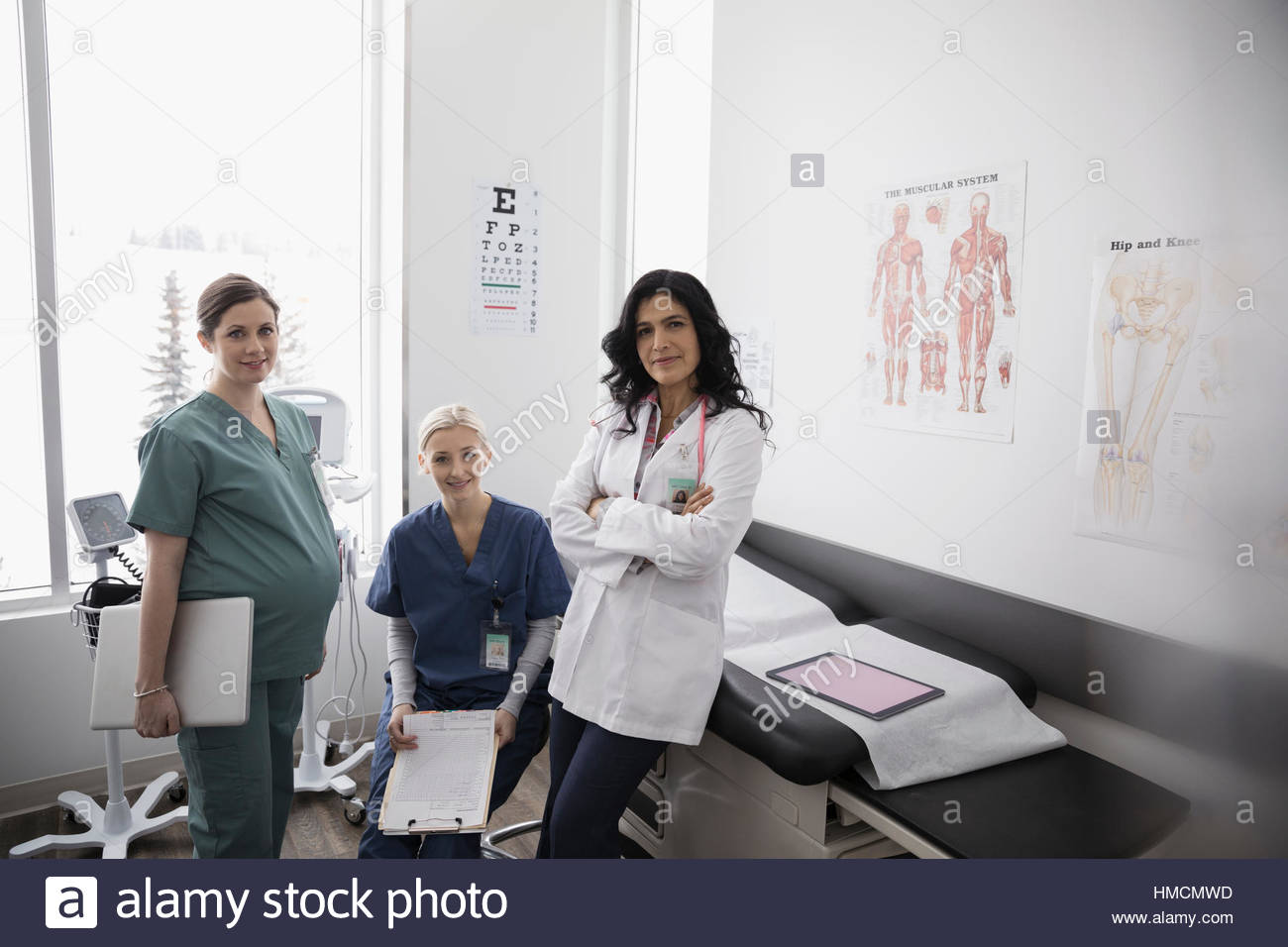 Portrait confident female doctor and nurses in medical examination room ...