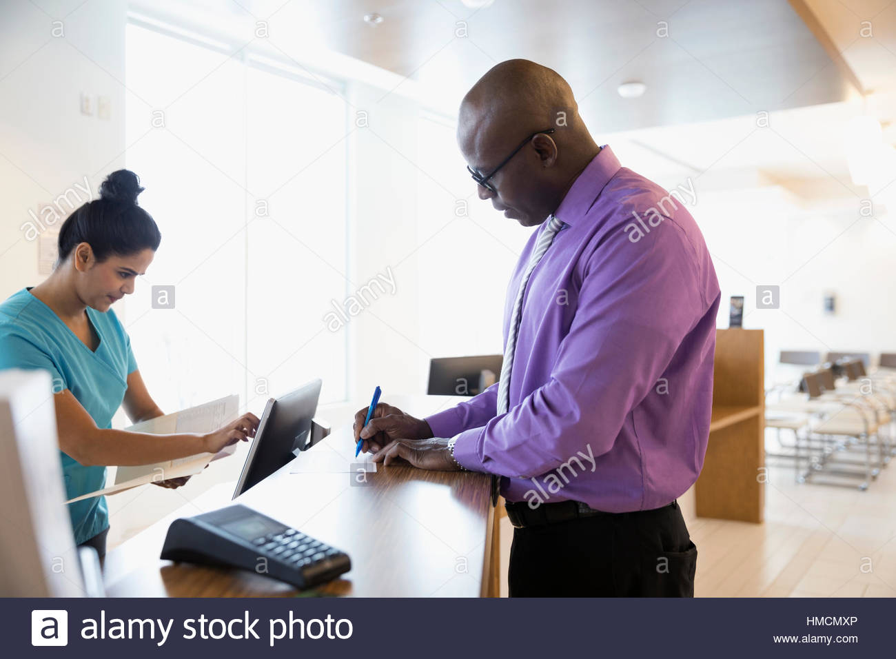 Male patient filling out paperwork at clinic check-in counter Stock ...