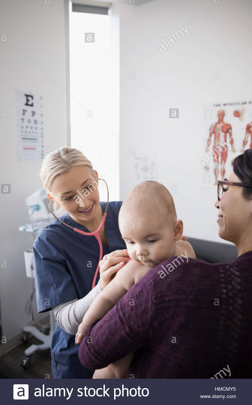 Female nurse using stethoscope on baby boy in clinic examination room ...