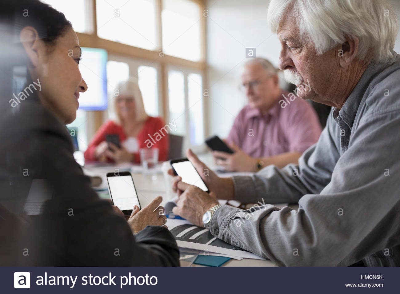 Teacher showing senior student how to use smart phone in classroom ...