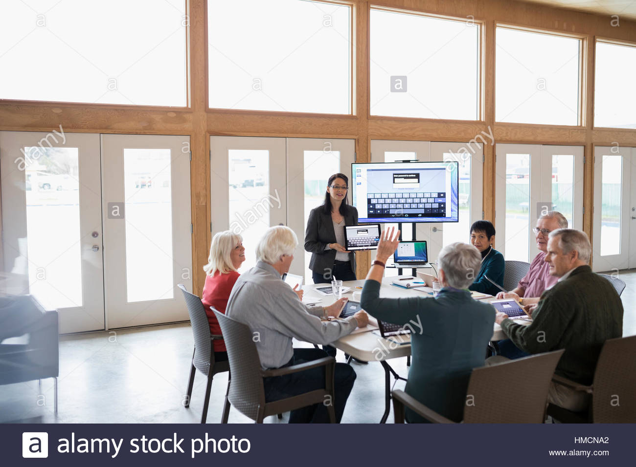 Teacher with laptop teaching senior students in classroom Stock Photo ...