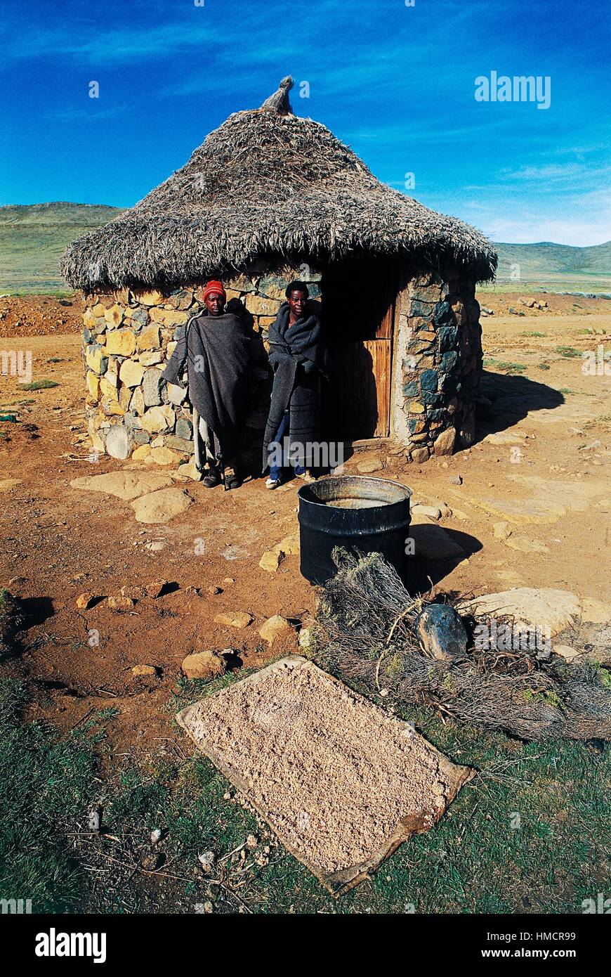 Men in front of a rondavel (round house with thatched roof and stone ...