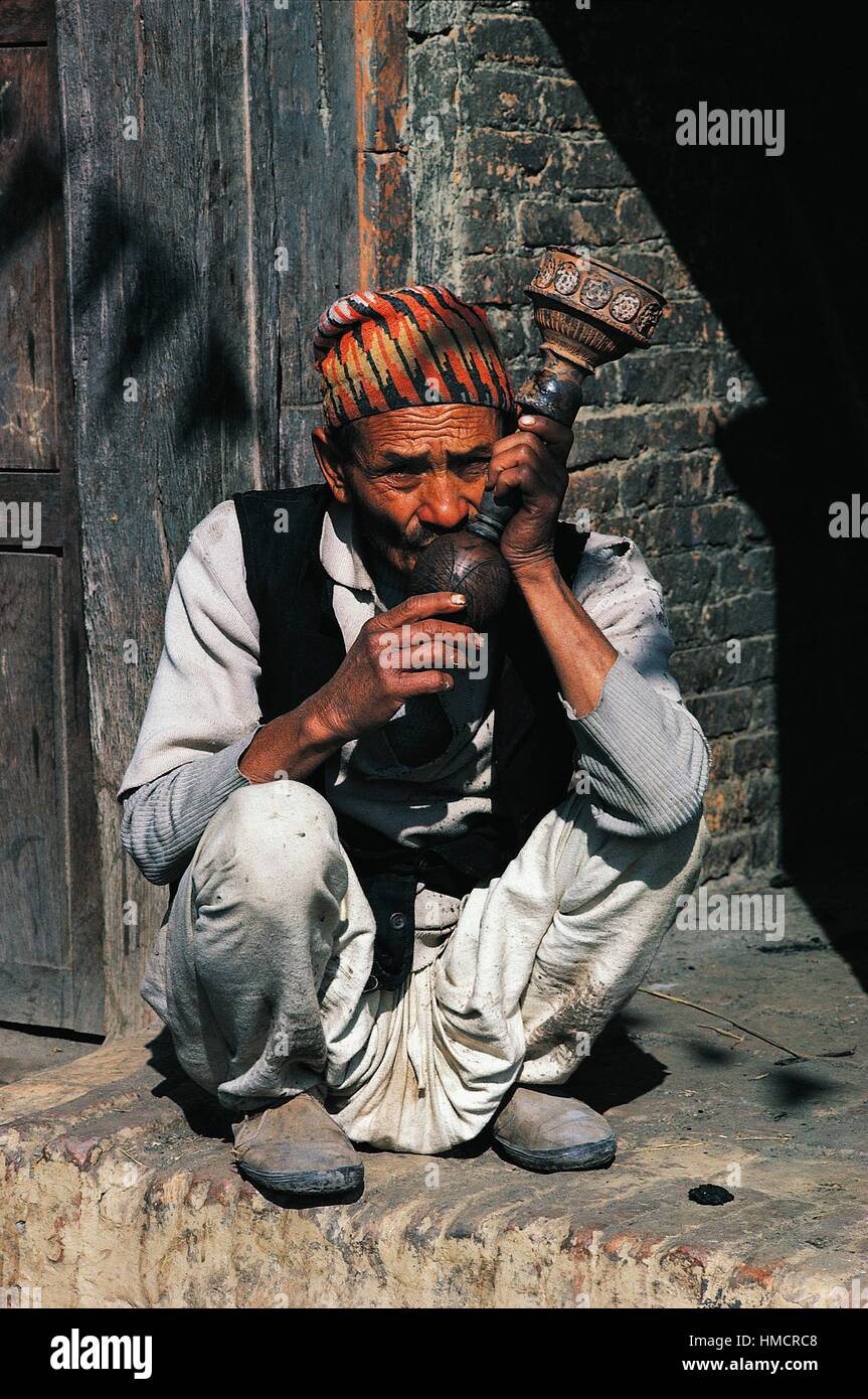 Man smoking a traditional wooden pipe, Bhaktapur, Kathmandu valley ...