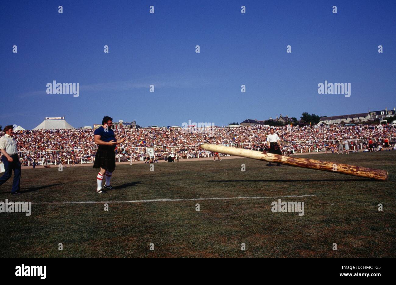 Athlete wearing a kilt throws a caber (large tapered wooden pole ...