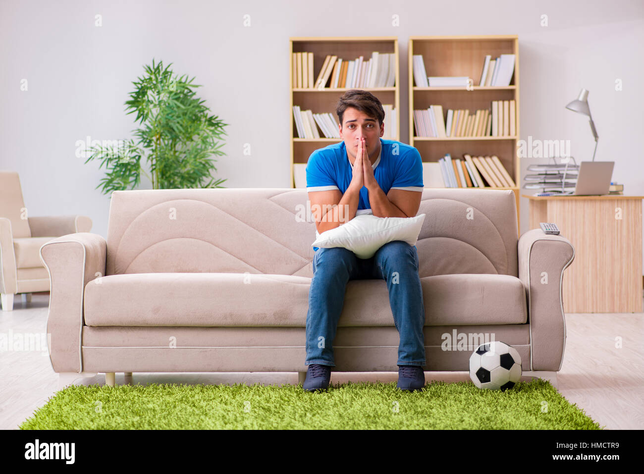 Man watching football at home sitting in couch Stock Photo - Alamy