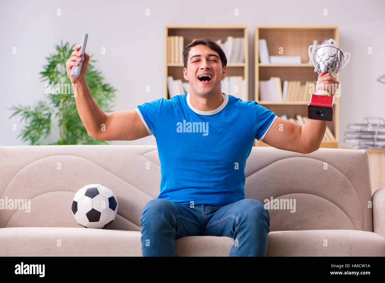 Man watching football at home sitting in couch Stock Photo - Alamy