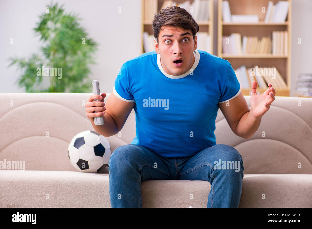 Man watching football at home sitting in couch Stock Photo - Alamy