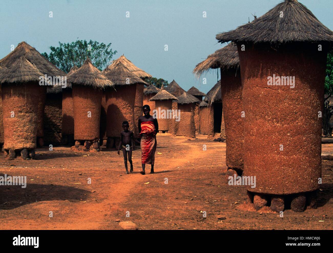 A woman and child among cylindrical barns with thatched roofs, village ...