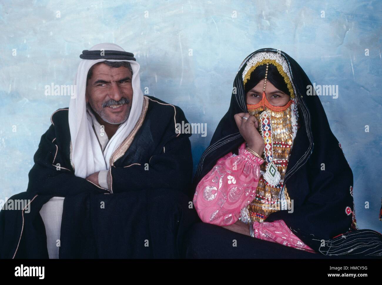 A pair of Bedouins, the woman is wearing a niqab decorated with gold ...