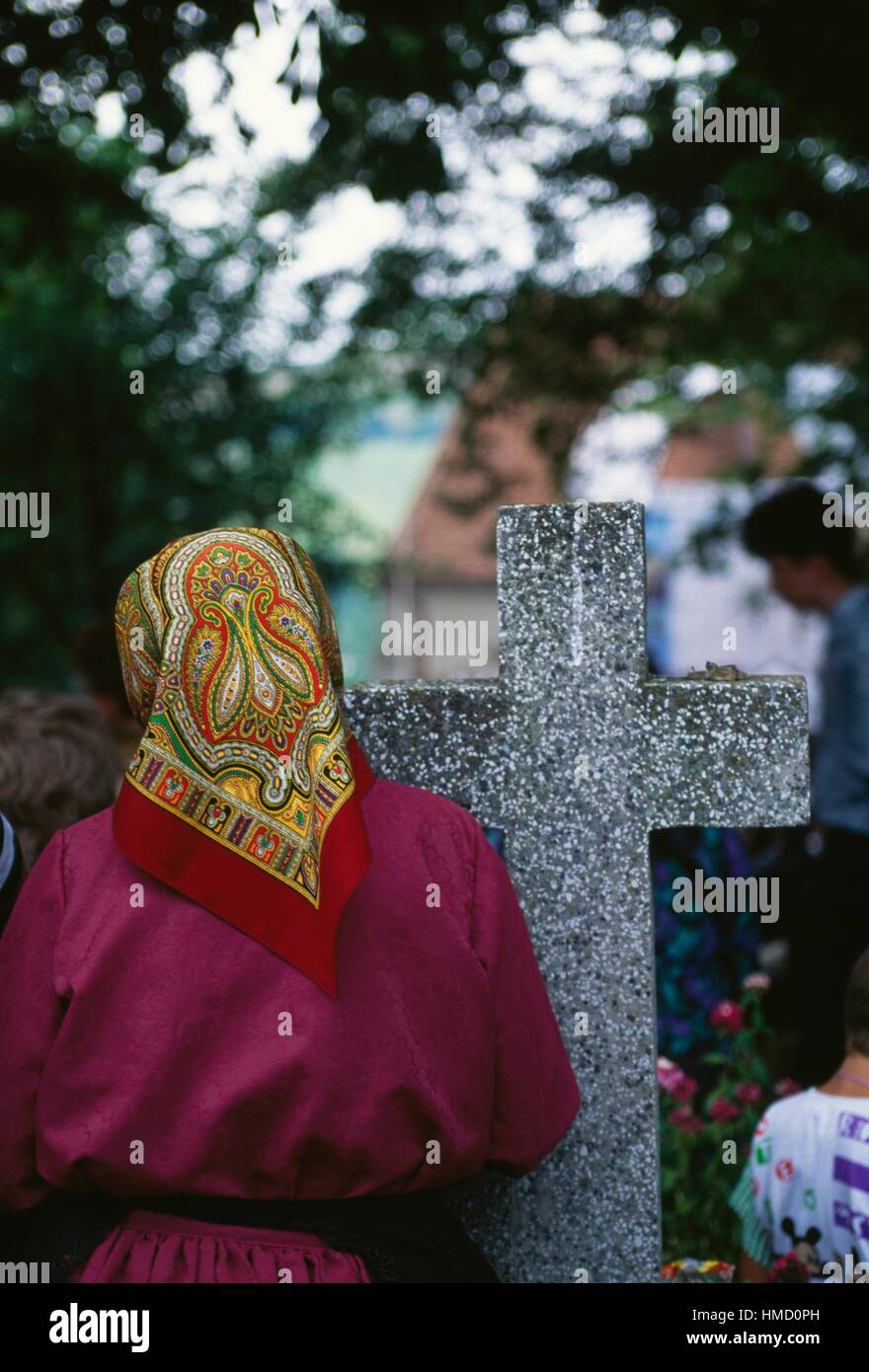 Woman wearing a head-scarf standing in front of a cross, religious ...
