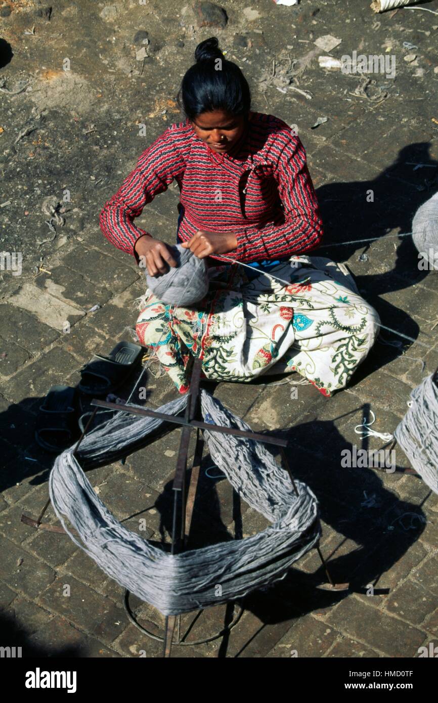 Woman sitting on the street winding wool on a skein-winder, Jawalakhel ...