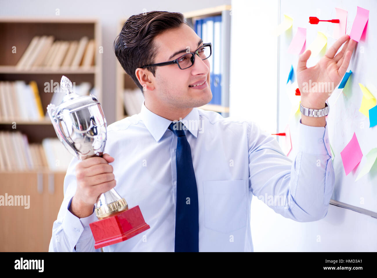 Young businessman receiving prize cup in office Stock Photo - Alamy
