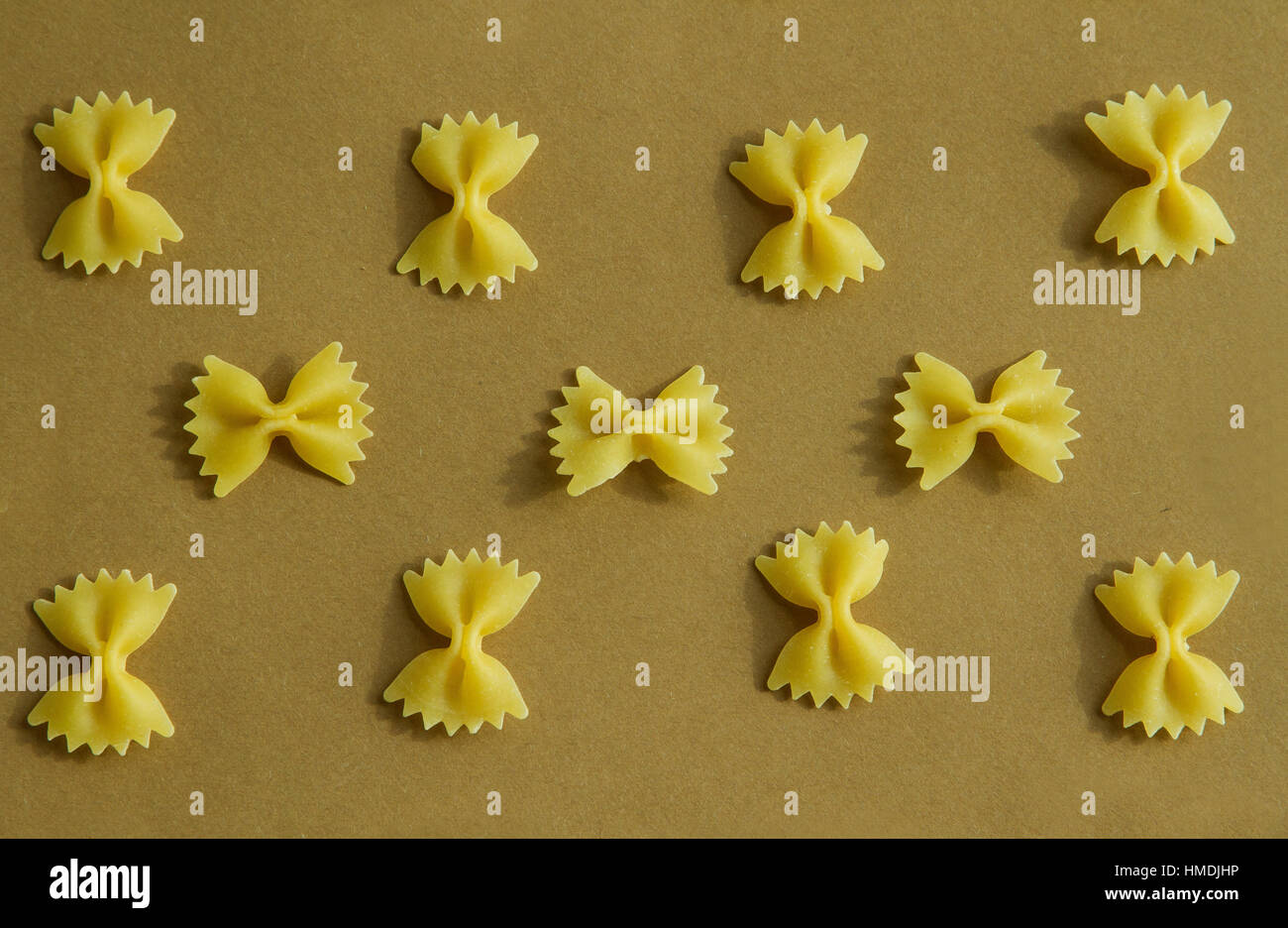 Makaroni or pasta bow shape in row on brown background Stock Photo - Alamy