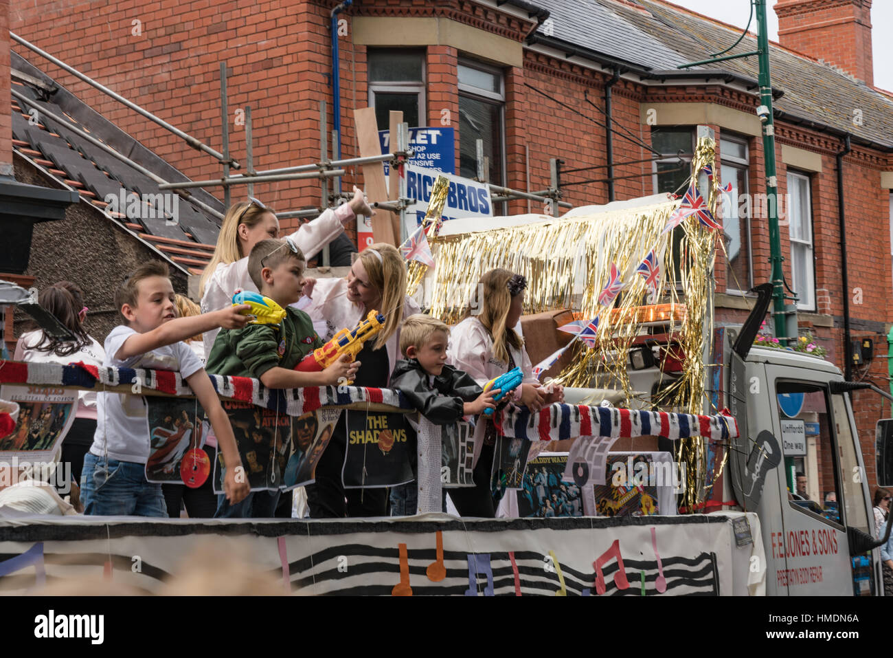 Children on a musically themed float spray spectators with water ...