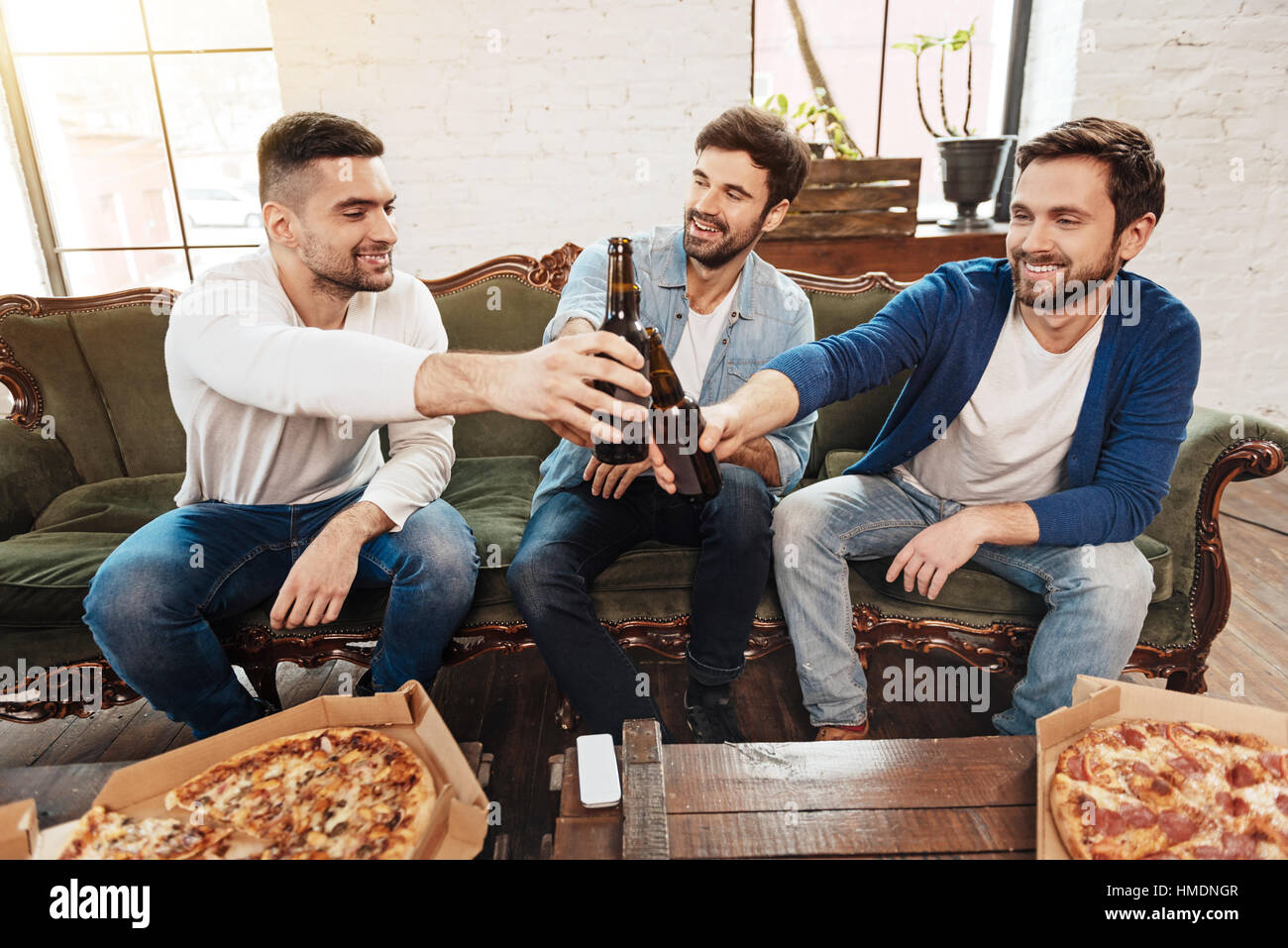 Positive joyful men raising beer bottles for toast Stock Photo - Alamy