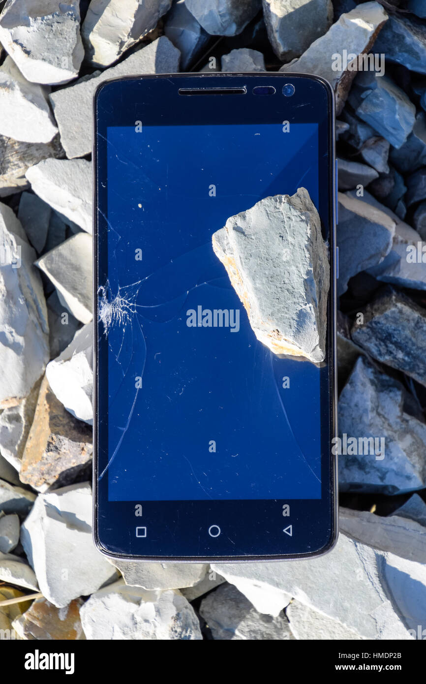 Frustrated phone on the rocks. Glass shattered on rocks on a smartphone ...
