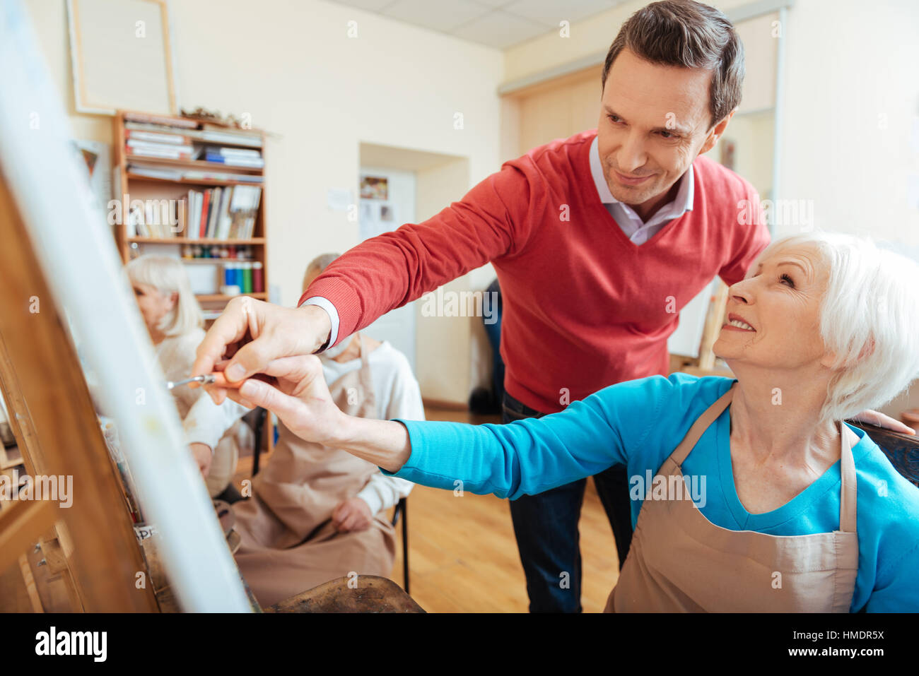 Smiling artist helping elderly woman in painting studio Stock Photo - Alamy