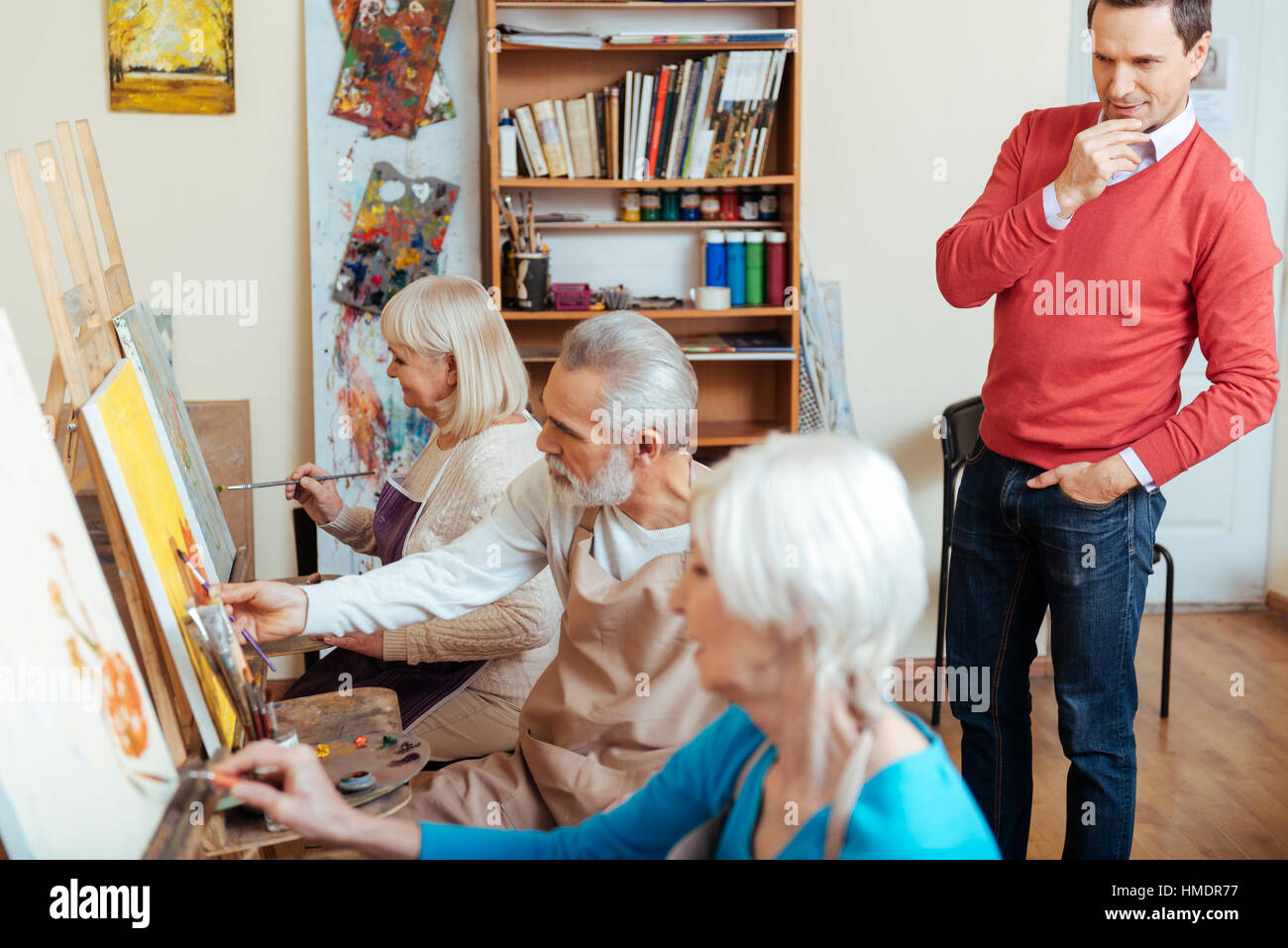 Concentrated artist controlling his colleagues in painting class Stock ...