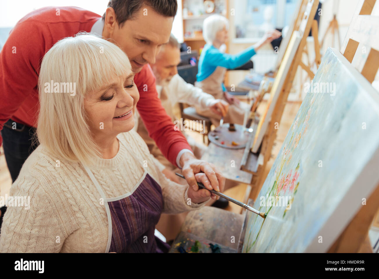 Glad man helping elderly woman in painting studio Stock Photo - Alamy
