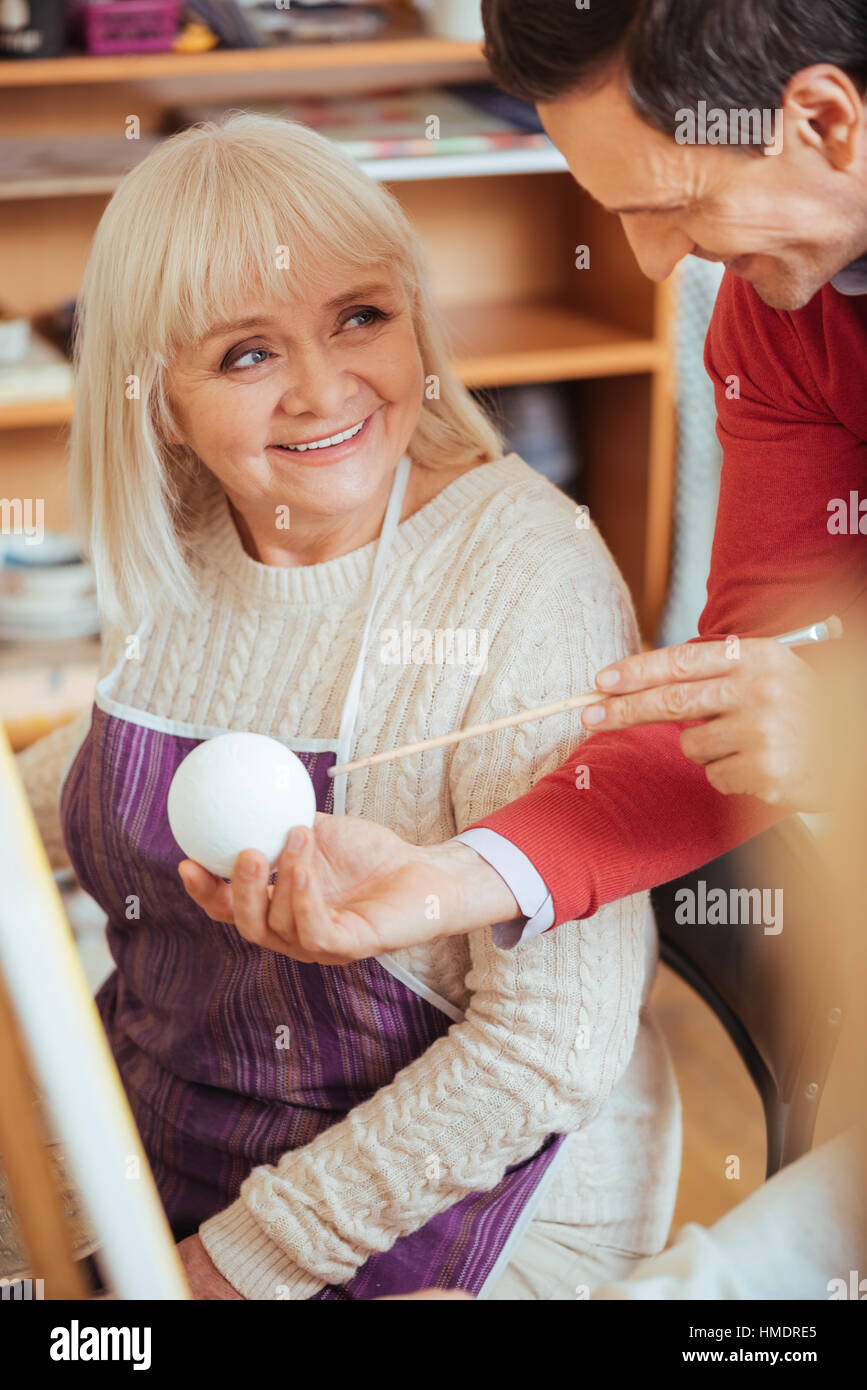 Smiling artist demonstrating a ball in painting studio Stock Photo - Alamy