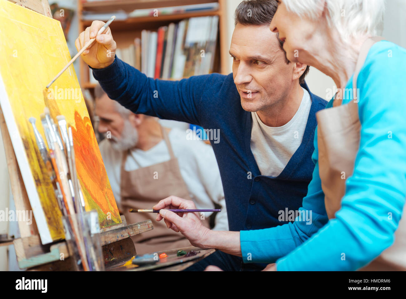 Delighted artist showing elderly woman how to paint Stock Photo - Alamy