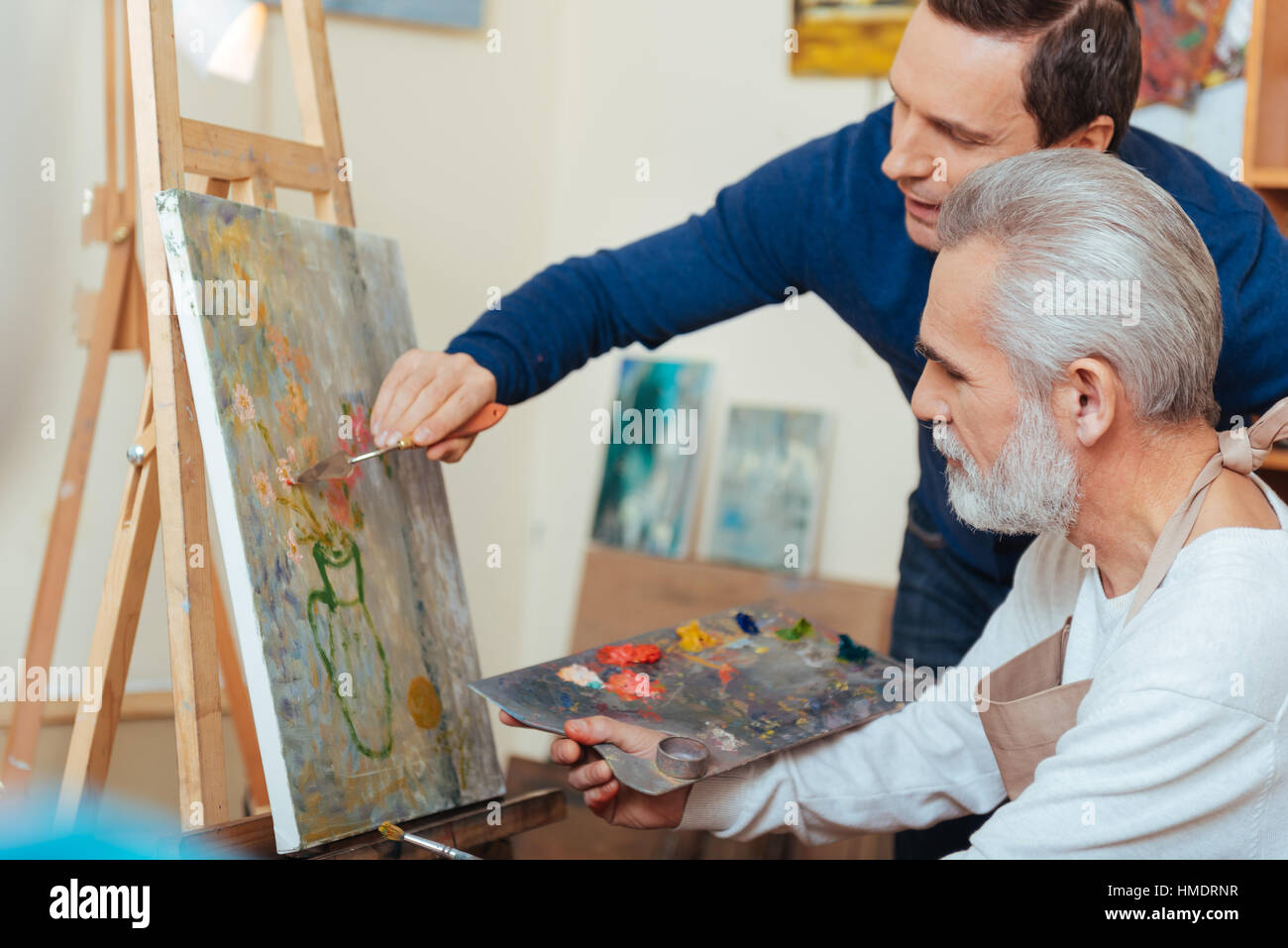Young artist helping elderly man in painting Stock Photo - Alamy